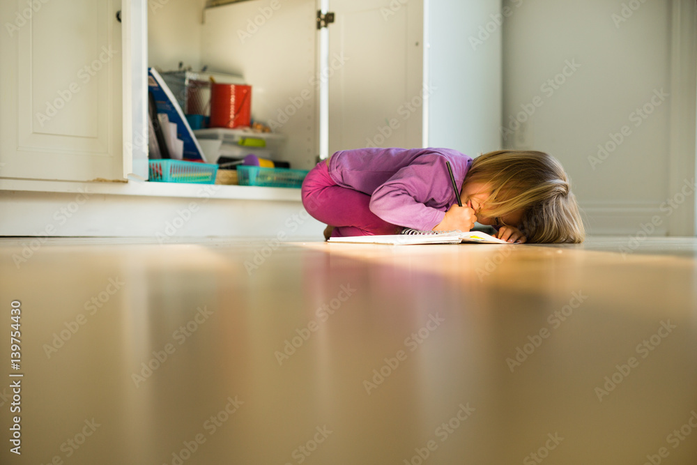 Preschool girl lying on floor drawing in drawing pad Stock Photo ...