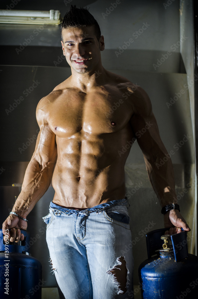 Muscular young man shirtless, carrying blue gas tanks, wearing only ...