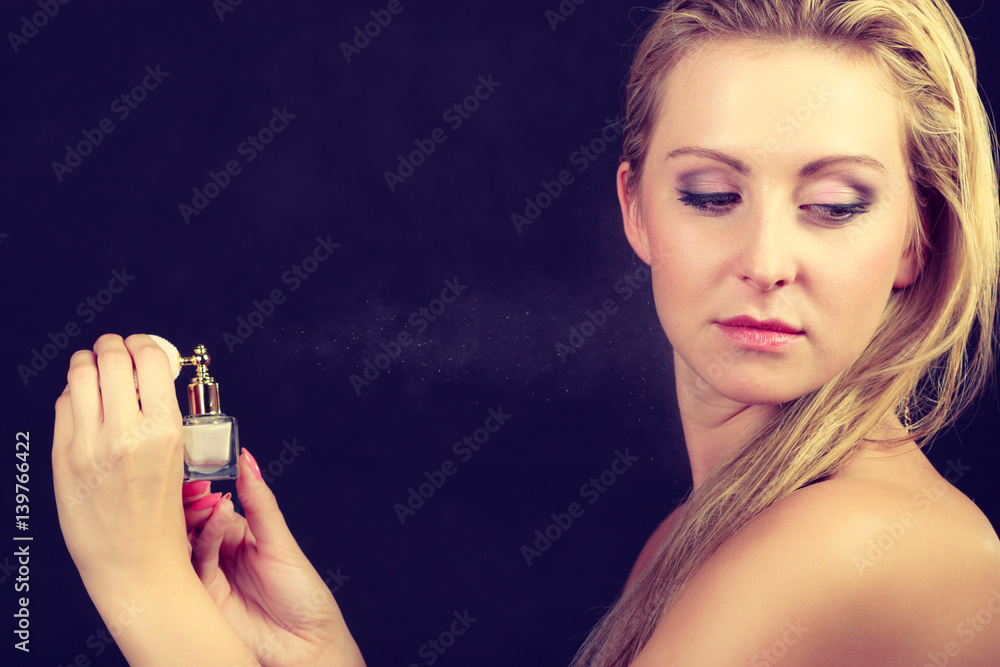 Beautiful woman with holding and applying perfume Stock Photo | Adobe Stock