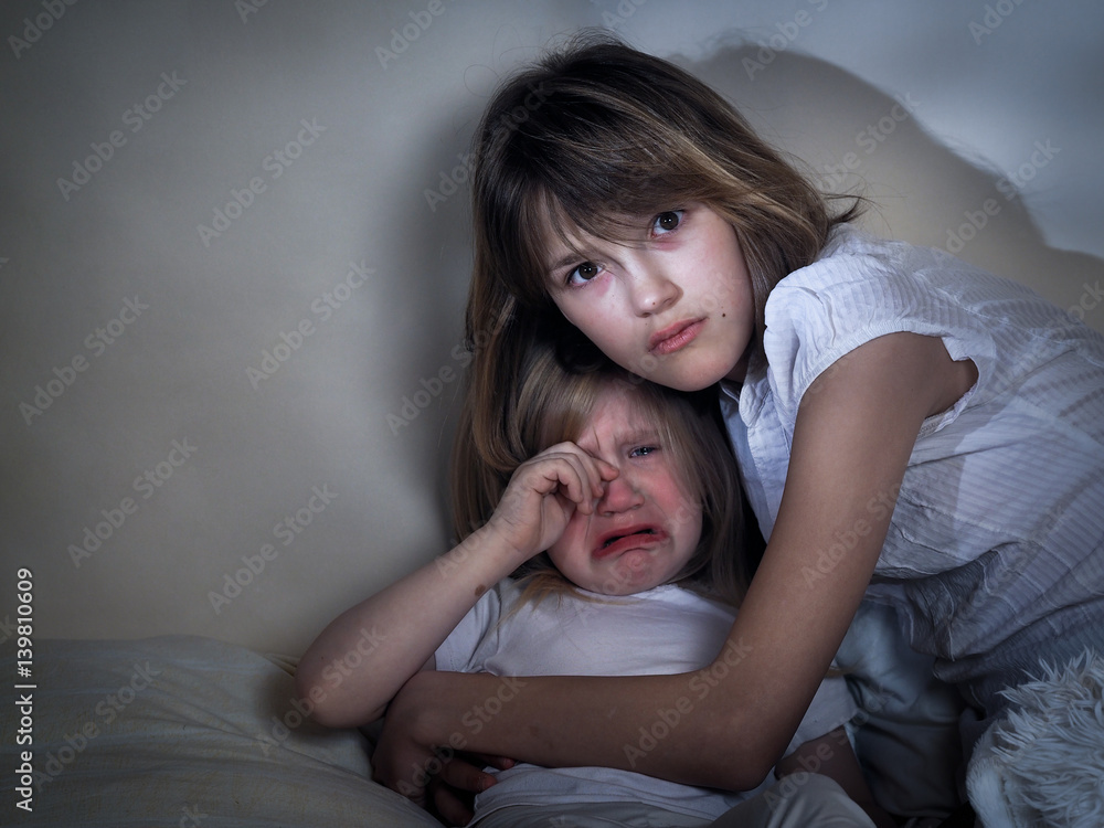 Sister teen hugs a crying little sister. Huge eyes, emotional eyes ...