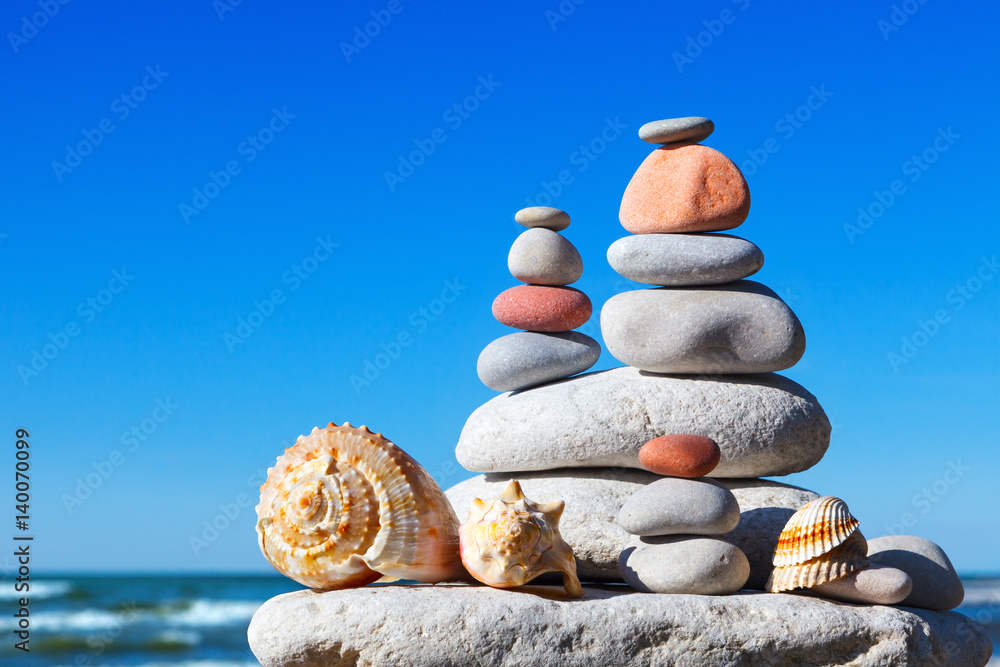 Pyramid of colorful rocks and shells on the sea background. The concept ...