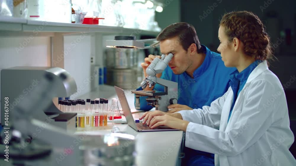 Lab researchers working with research microscope. Laboratory research teamwork. Laboratory ...