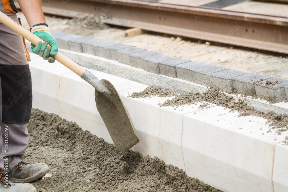 Construction worker working hard leveling concrete pavement outdoors ...
