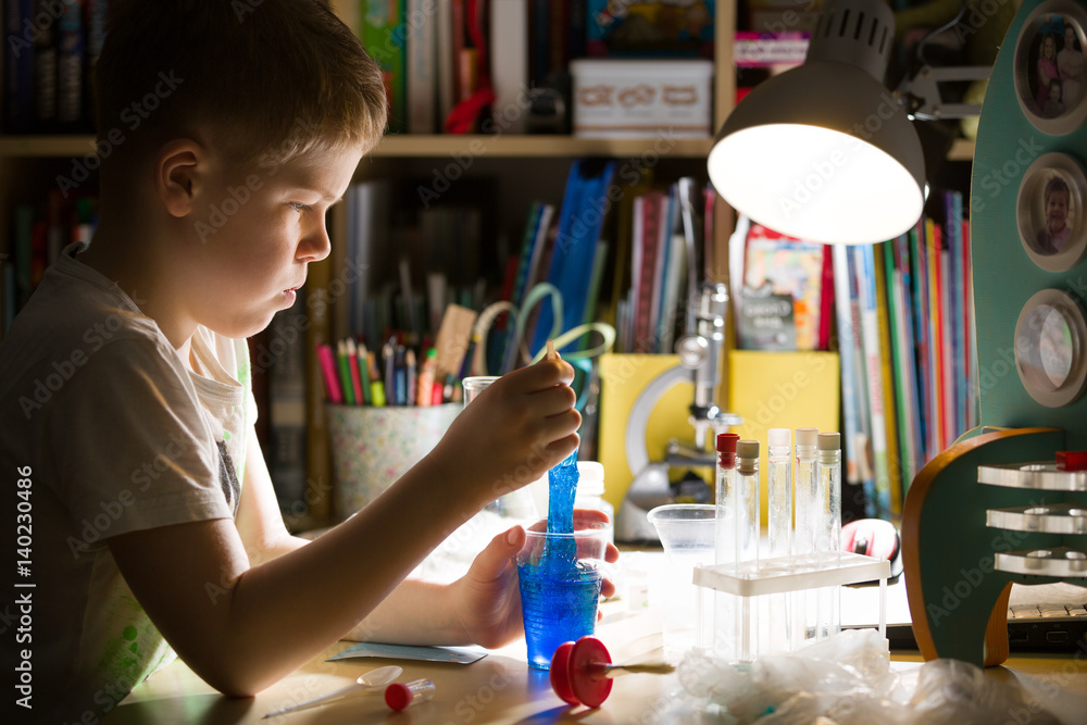 Cute elementary school boy looking into microscope at his desk at home ...