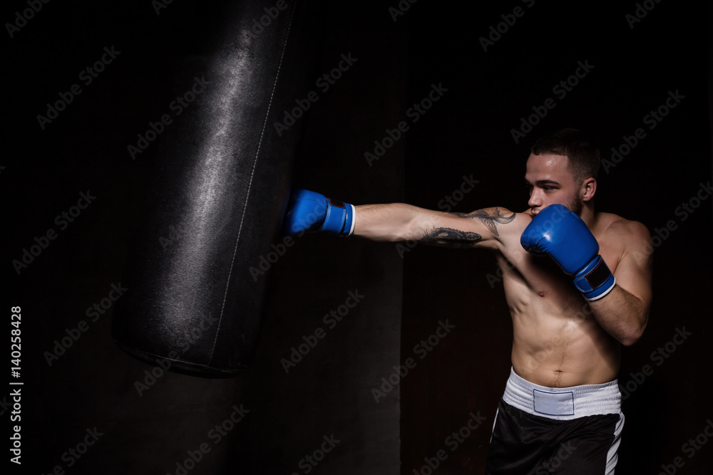 Athlete boxer man punching a punching bag Stock Photo | Adobe Stock