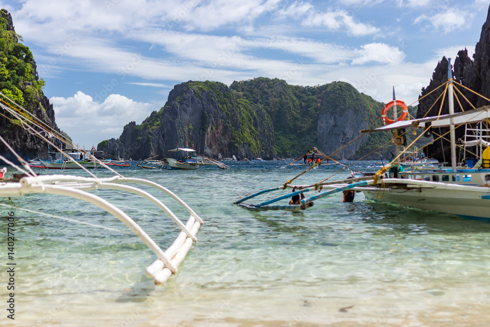 Fotka „Filipino pump boats on a sunny day landed ashore on a white sand ...