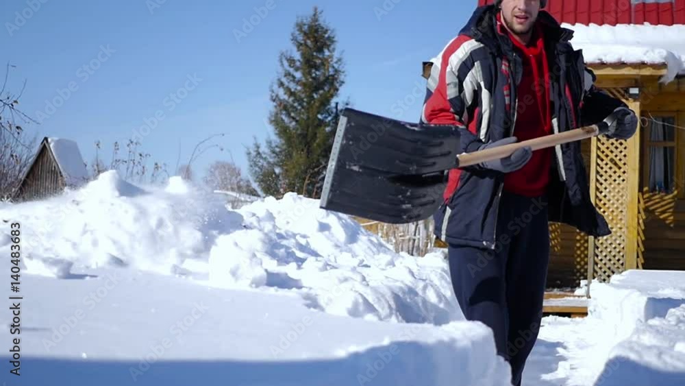 Throwing snow on a pile. Man with a shovel in his hand in the front of ...