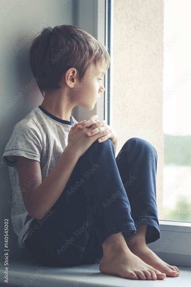 Sad child sitting on window shield and looking out the window Stock ...