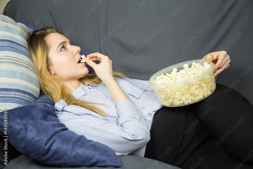 Young pretty blond caucasian woman with light brown eyes lying on sofa ...