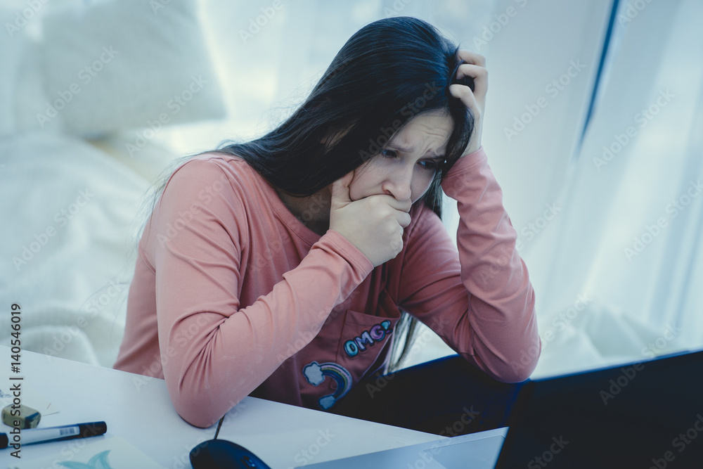 Foto de sad and scared female teenager with computer laptop suffering ...