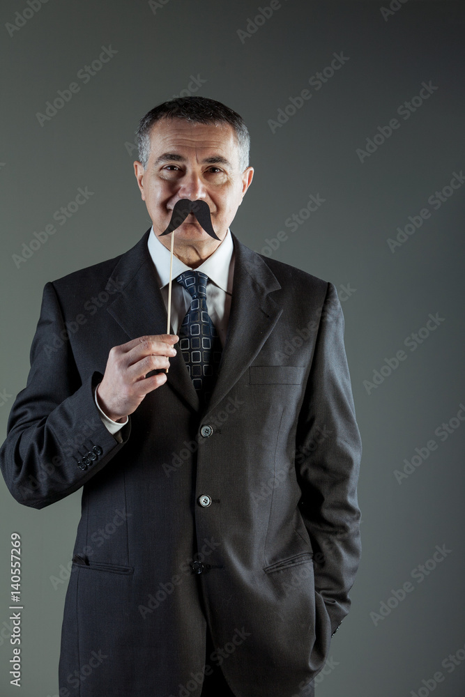 Smiling businessman holding a mustache Stock Photo | Adobe Stock