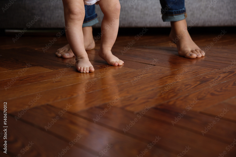 chubby feet of a baby doing his first steps on a wood floor with his ...