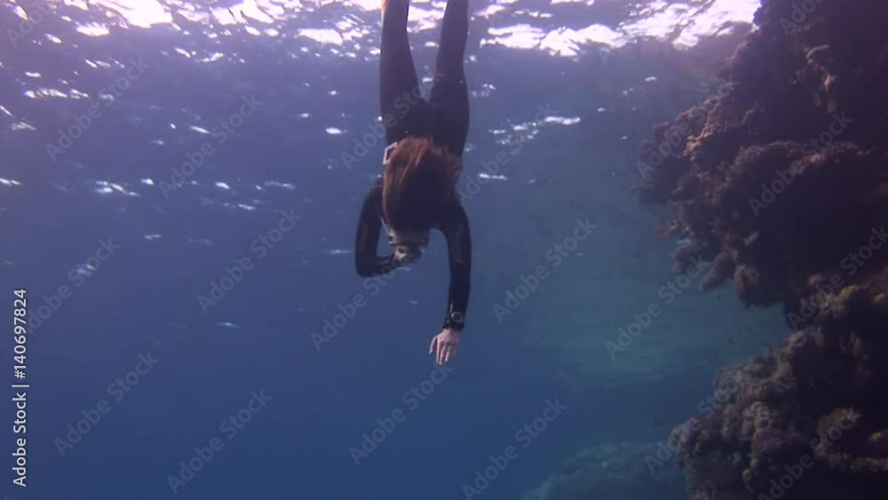 Underwater model free diver swims in clean transparent blue water in ...