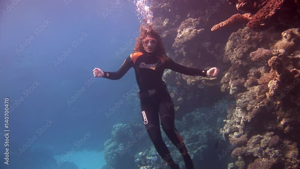 Stockvideon Underwater model free diver swims in clean transparent blue ...