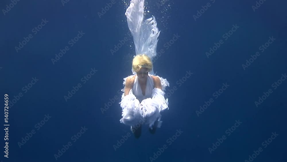 Young girl model underwater white angel costume on blue background in ...