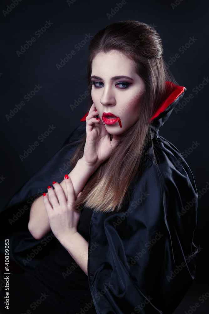 Portrait of a beautiful vampire girl in a cloak of dracula. Stock Photo ...