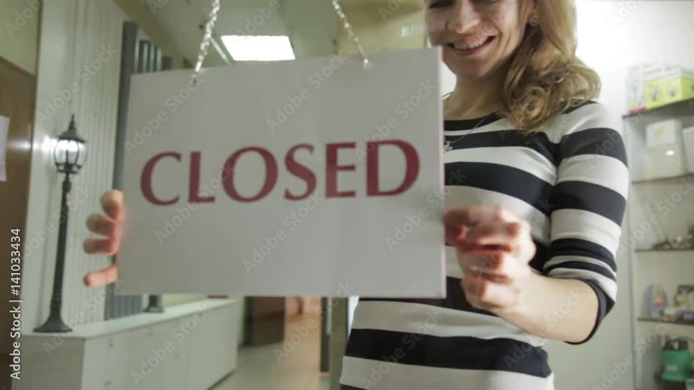 open sign is turned to closed in a storefront window. woman flipping ...