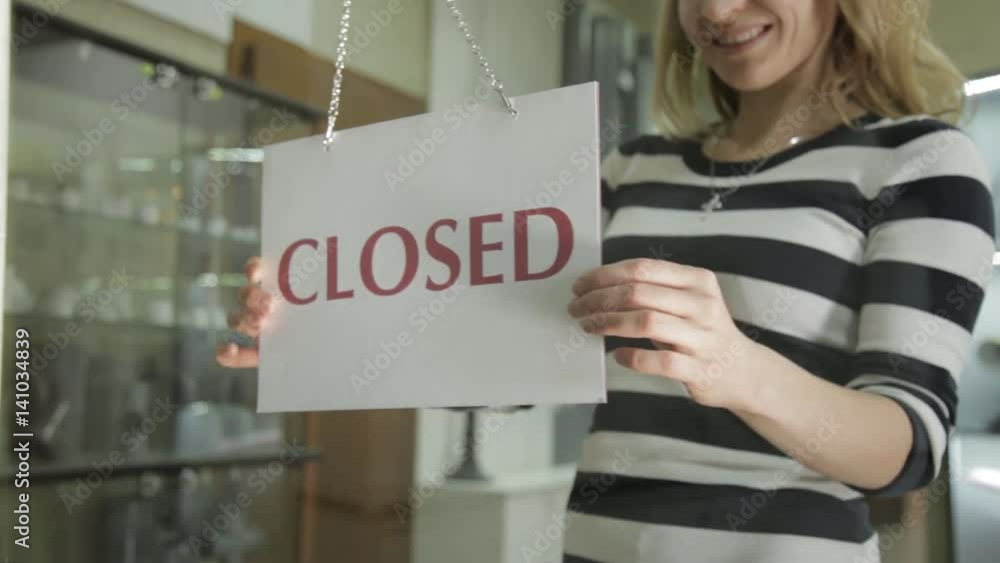 open sign is turned to closed in a storefront window. woman flipping ...