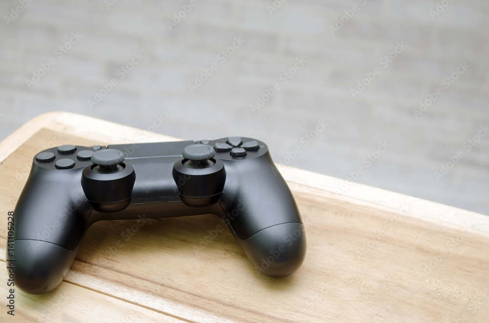 Video game controller on wooden desk with brick wall background, copy ...