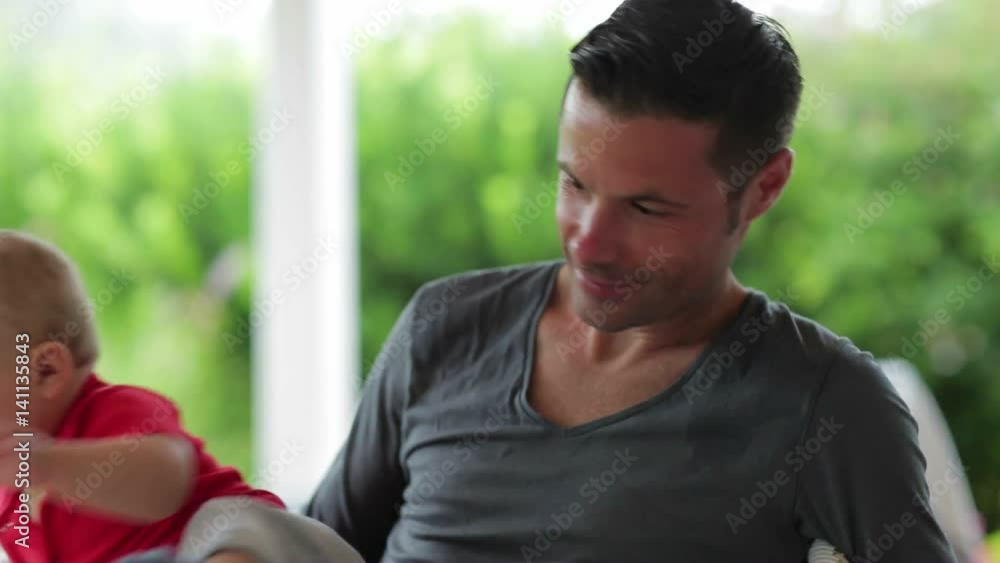 Baby almost falls from his father's lap. Dad catches his infant baby ...