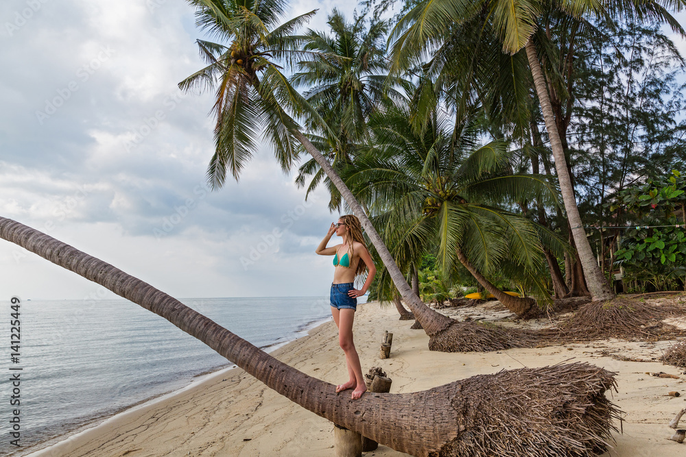 Woman on a fallen palm tree Stock Photo | Adobe Stock