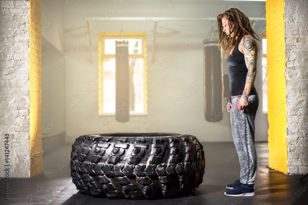 Crossfit with car tire . The girl is training with a huge car tire. A ...