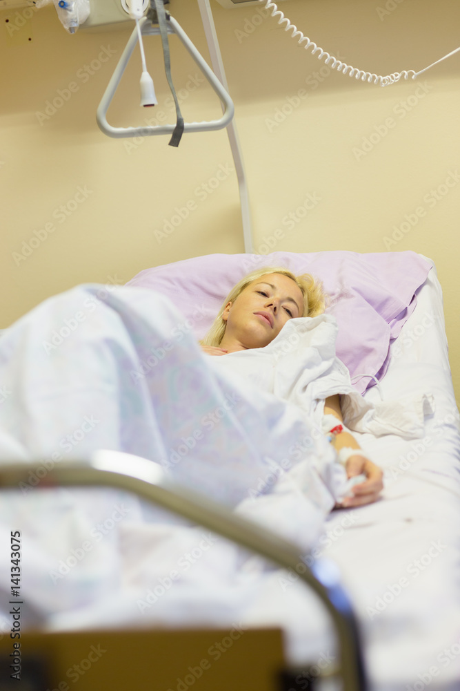 Bedridden female patient lying in hospital bed, recovering after ...