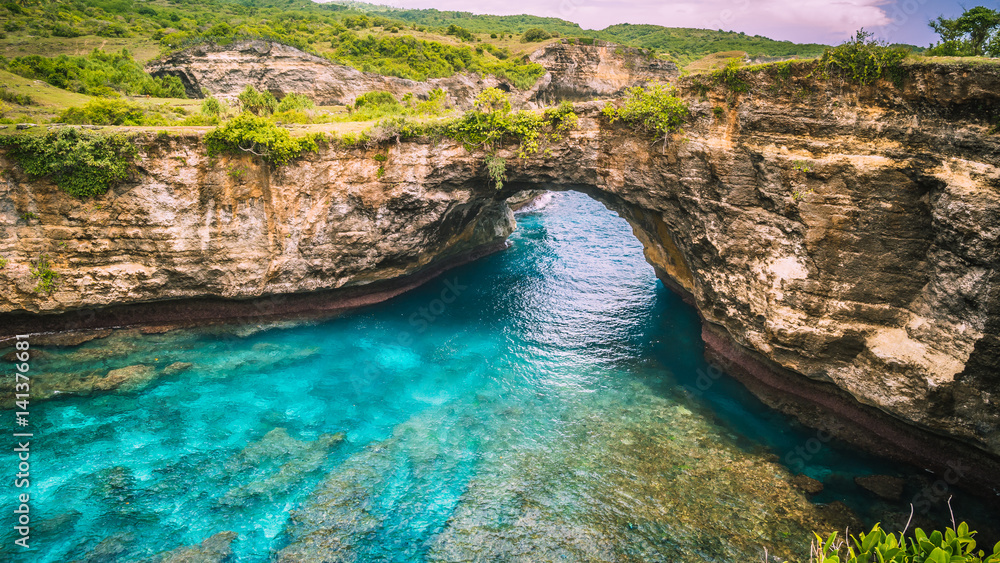 Rock coastline. Stone arch over the sea. Broken beach, Nusa Penida ...