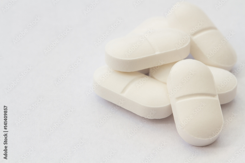 A stack or pile of white painkilling tablets, drugs or pills on an ...