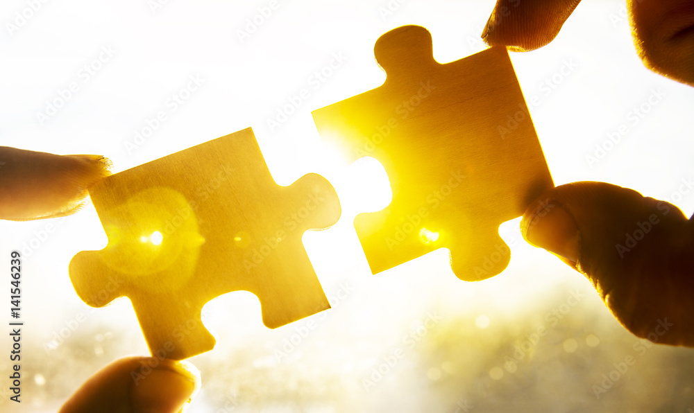 two hands trying to connect couple puzzle piece with sunset background ...