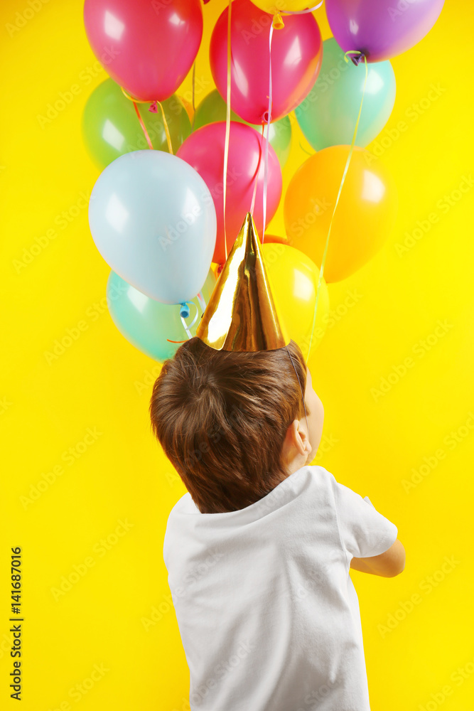 Cute birthday boy with colorful balloons on yellow background Stock ...