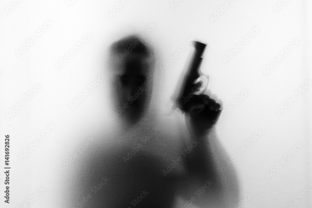 Shadow of horror man killer with a gun in his hand.Dangerous man behind ...