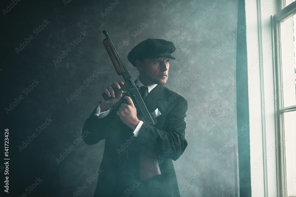 Retro 1920s english gangster wearing flat cap and suit. Standing with ...