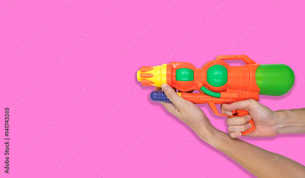 Hand holding gun water toy on pink background. Free space for text ...