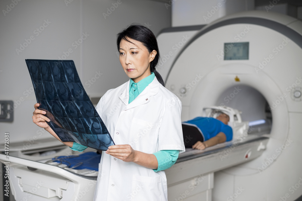 Doctor Analyzing X-ray While Patient Lying On CT Scan Machine Stock ...