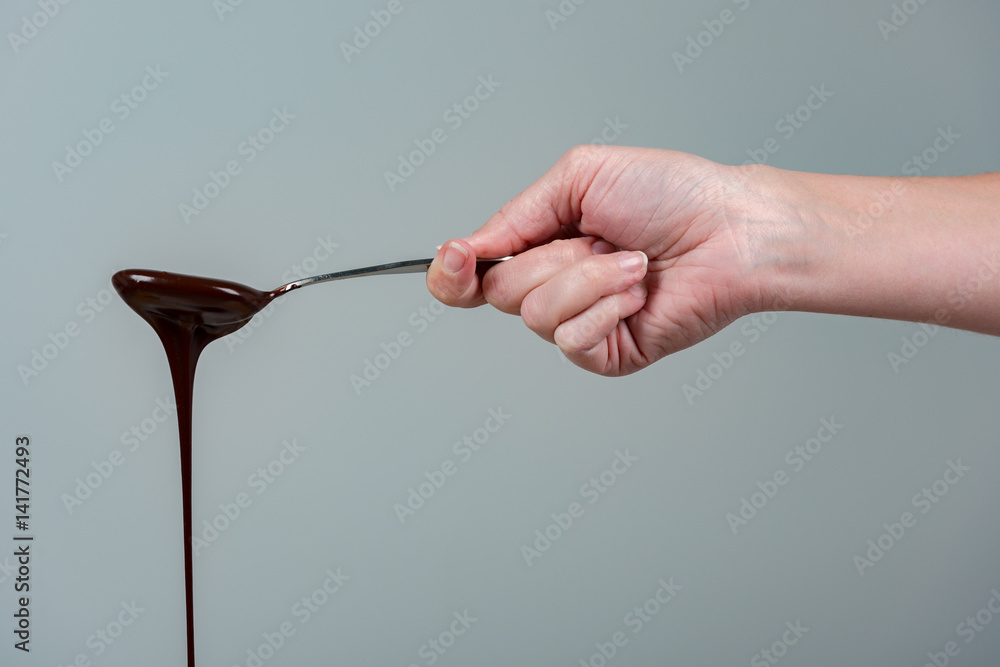 Female hand holding a spoon with dripping chocolate sauce Stock Photo ...
