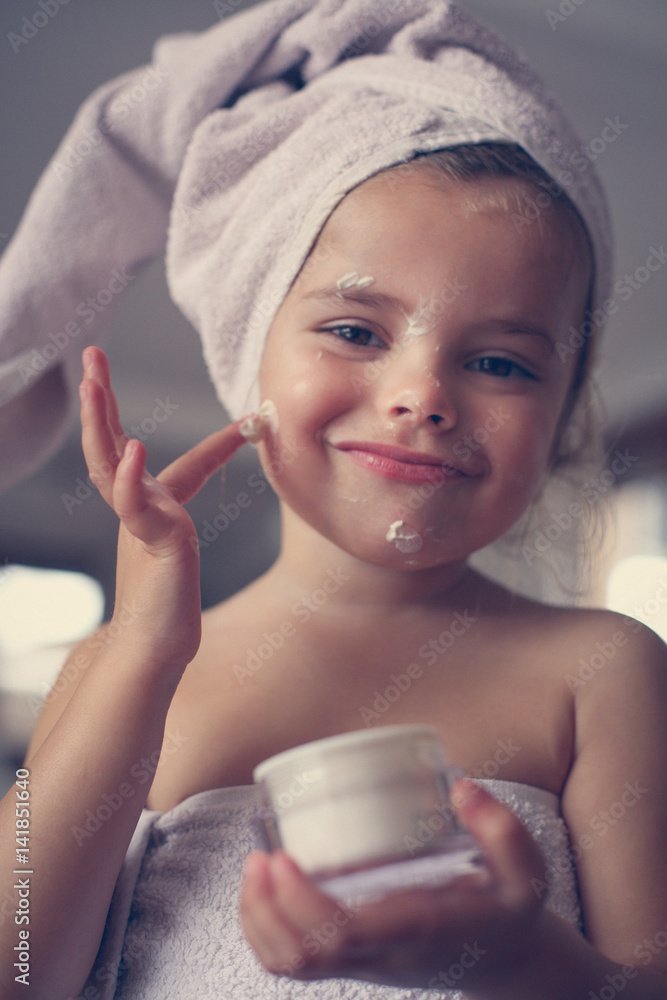 Little girl putting cream on her face Stock Photo | Adobe Stock