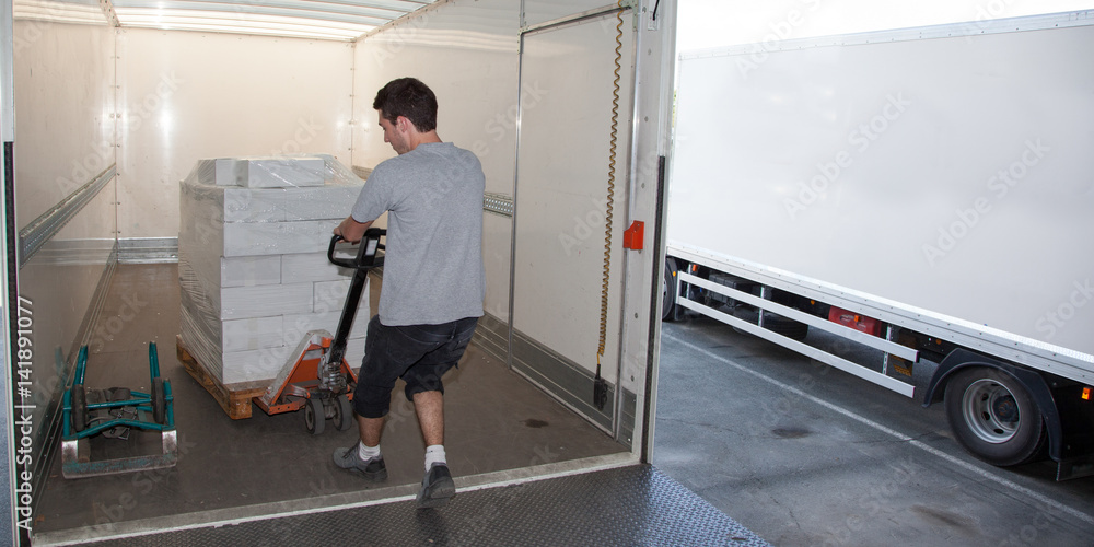 truck driver empties his truck with a pallet pull at docks truck ...