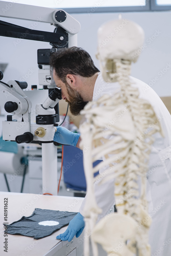 Scientist in laboratory that looks at microscope and a skeleton Stock ...