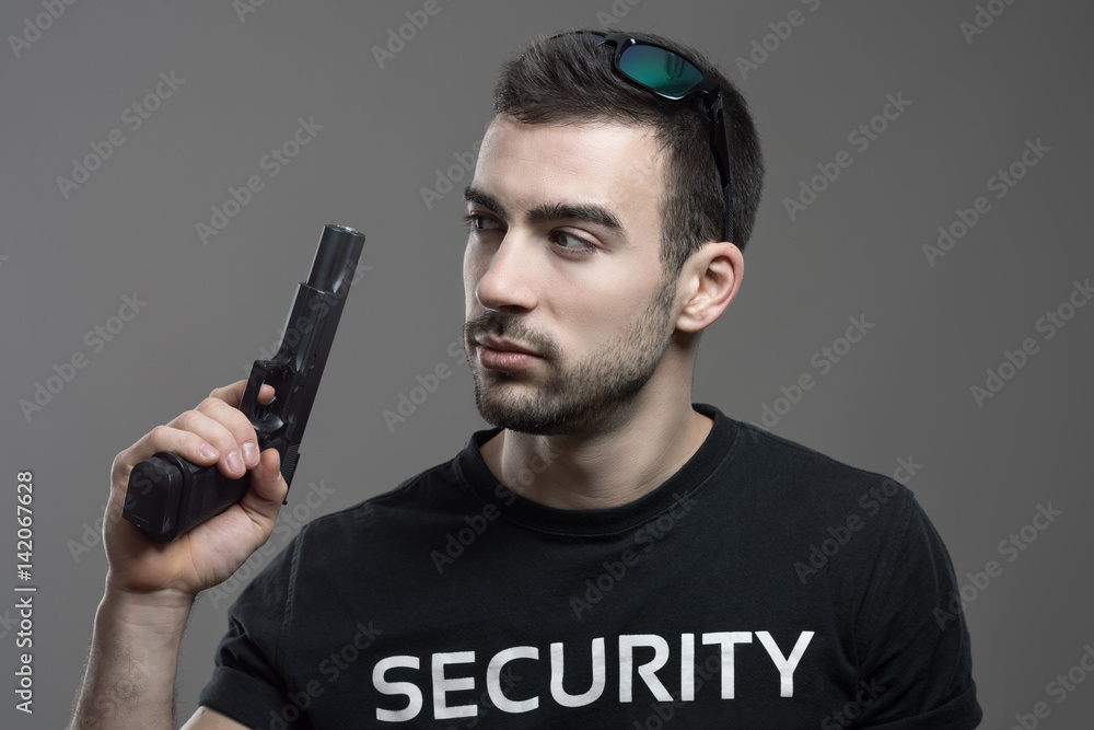 Cautious alerted security guard holding gun looking back over shoulder ...