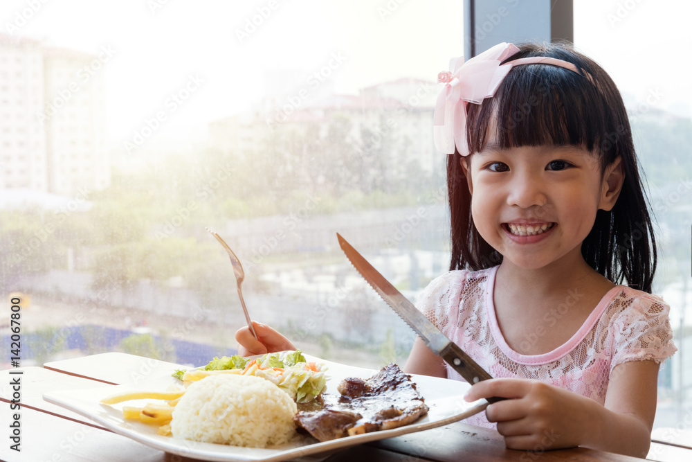 Smiling Asian Chinese little girl eating lamb steak with rice Stock ...
