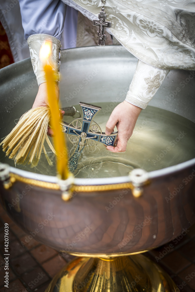 The priest blesses the water, the Holy water in the tank, the priest ...