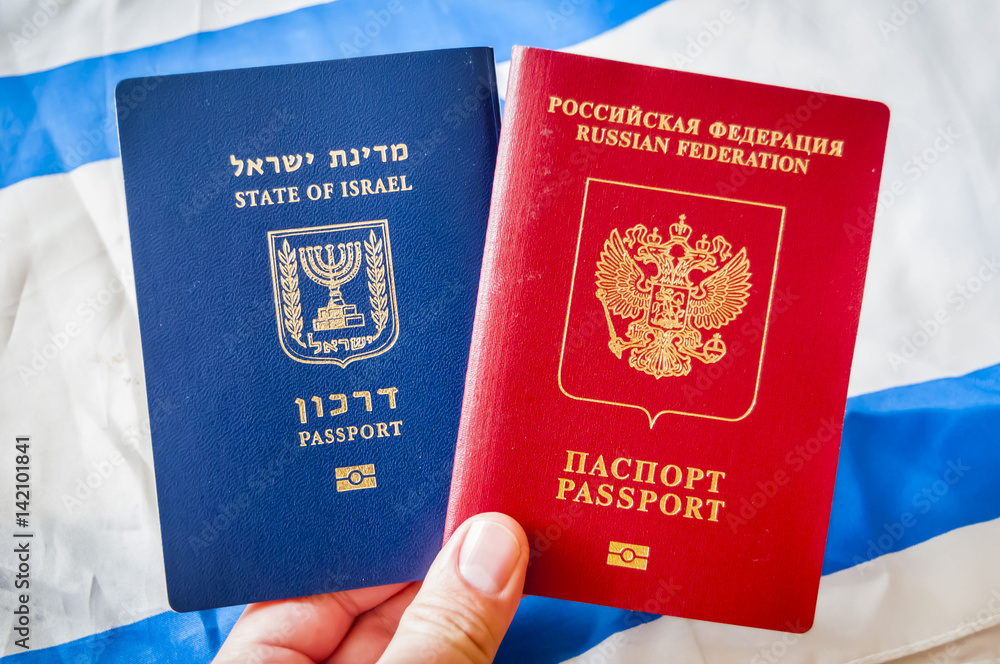 Hand holding two foreign passports: the passport of State of Israel and ...