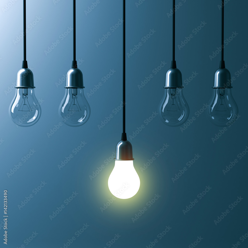 One hanging light bulb glowing different and standing out from unlit ...