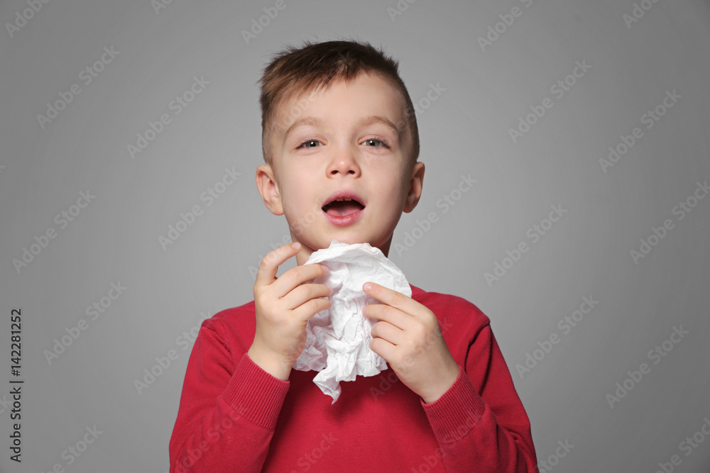 Cute little boy sneezing in tissue on gray background Stock-Foto ...