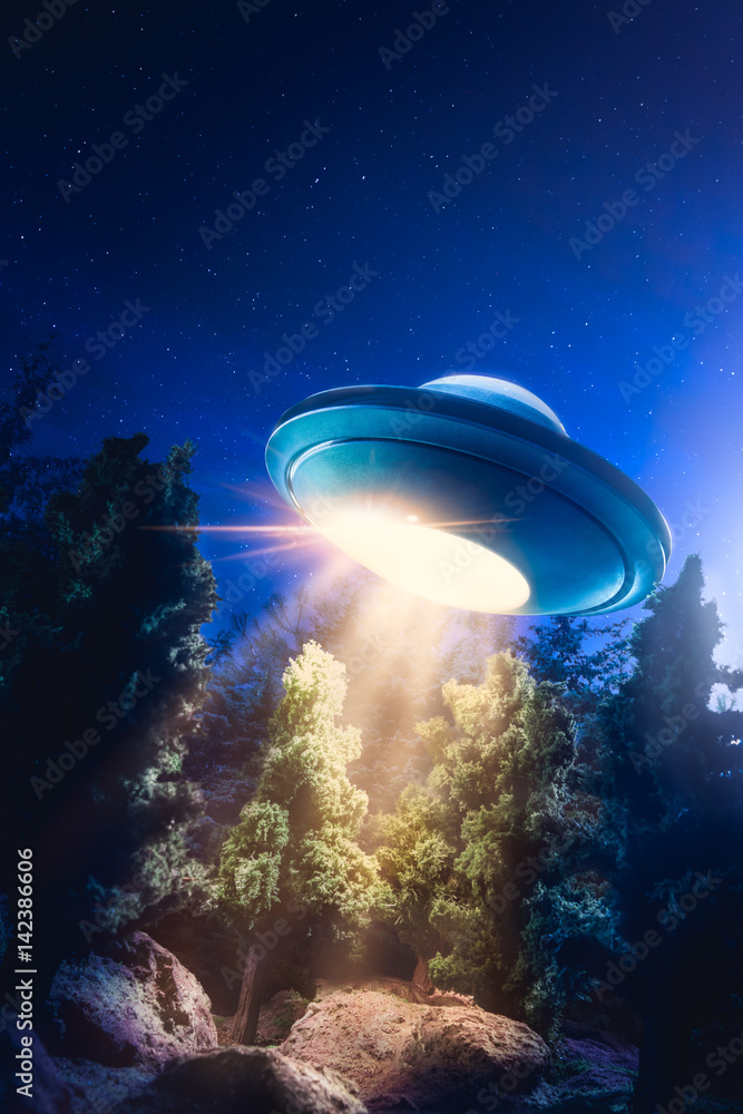 High contrast image of UFO flying over a forest with light beam at ...