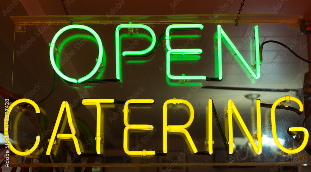 Open and catering neon advertising sign in the window of a restaurant ...