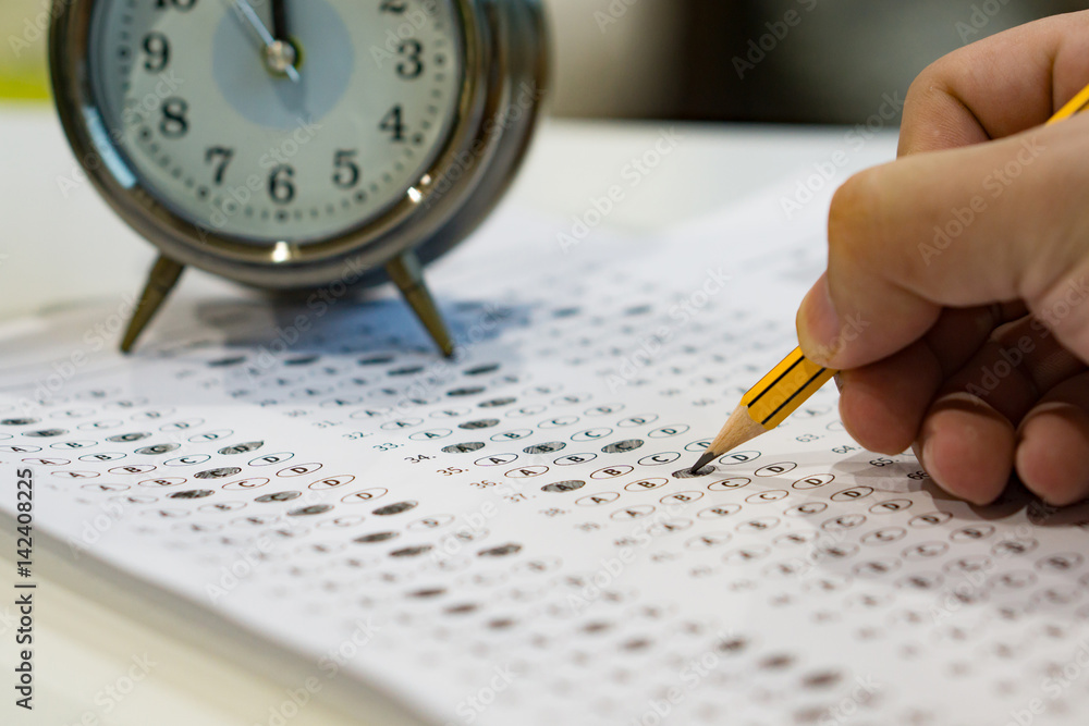 A pencil sitting on a test bubble sheet and alarm clock, optical form ...