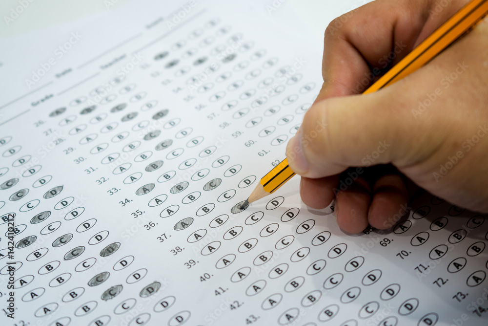 A pencil sitting on a test bubble sheet and alarm clock, optical form ...