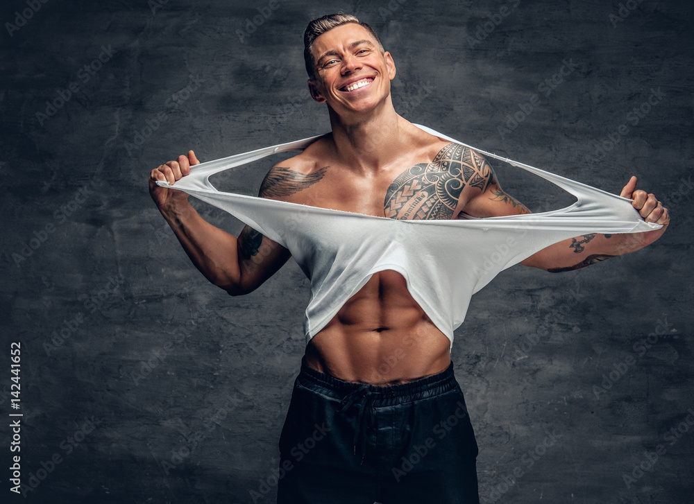 Athletic male with a tattoo ripping t shirt on his chest. Stock Photo ...